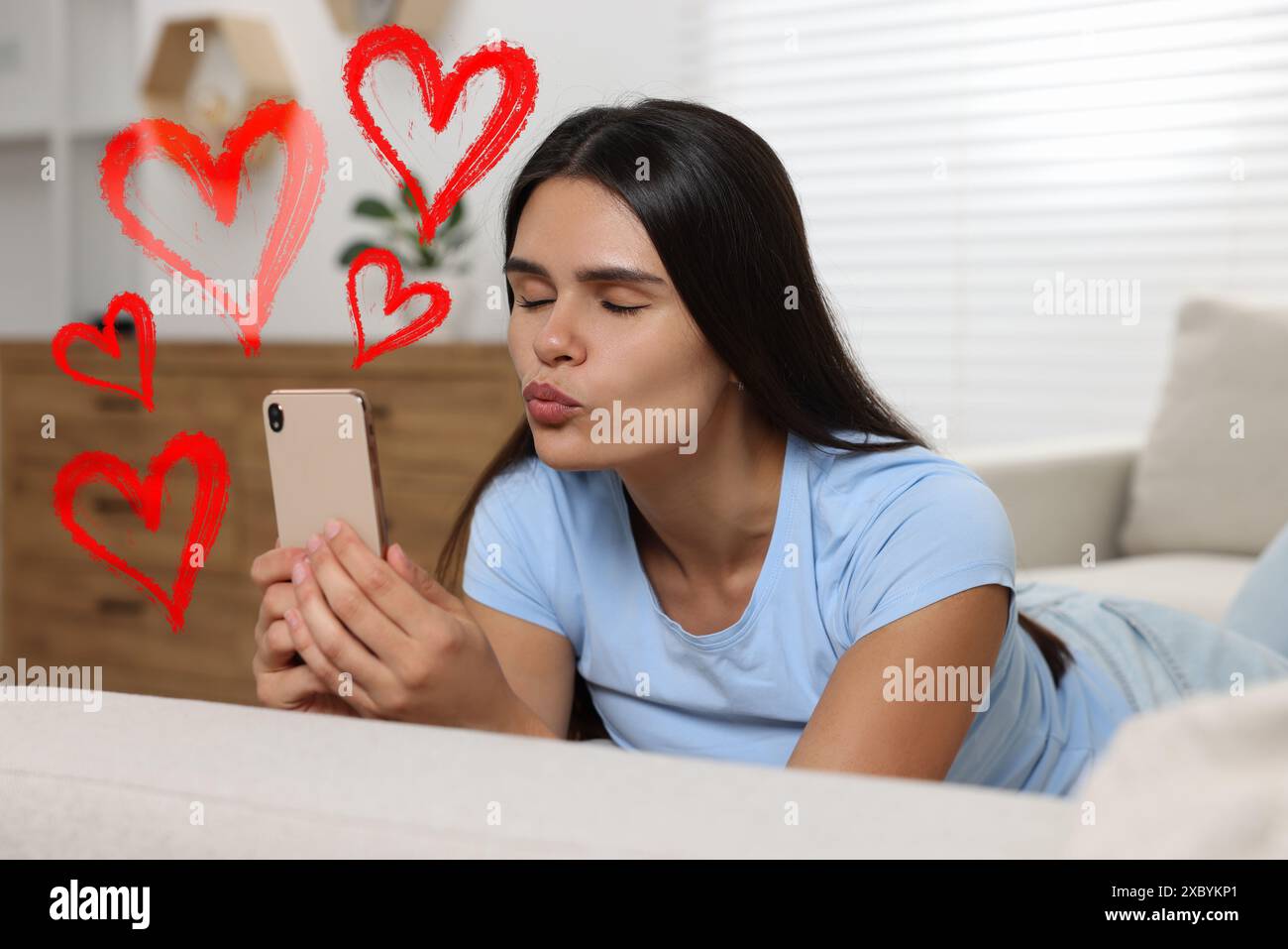 Long distance relationship. Young woman sending air kiss to her loved ...