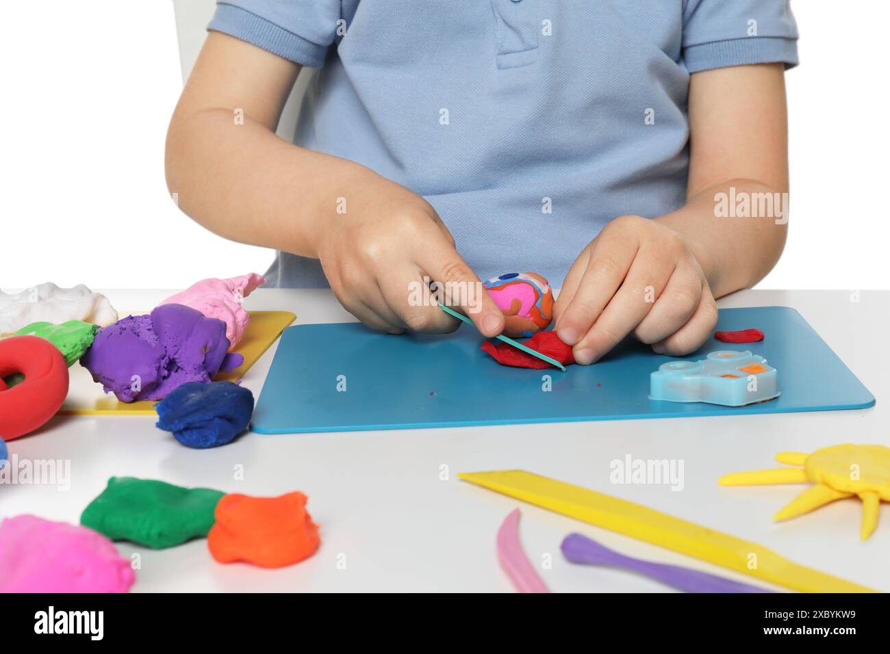 Little boy sculpting with play dough at table on white background ...