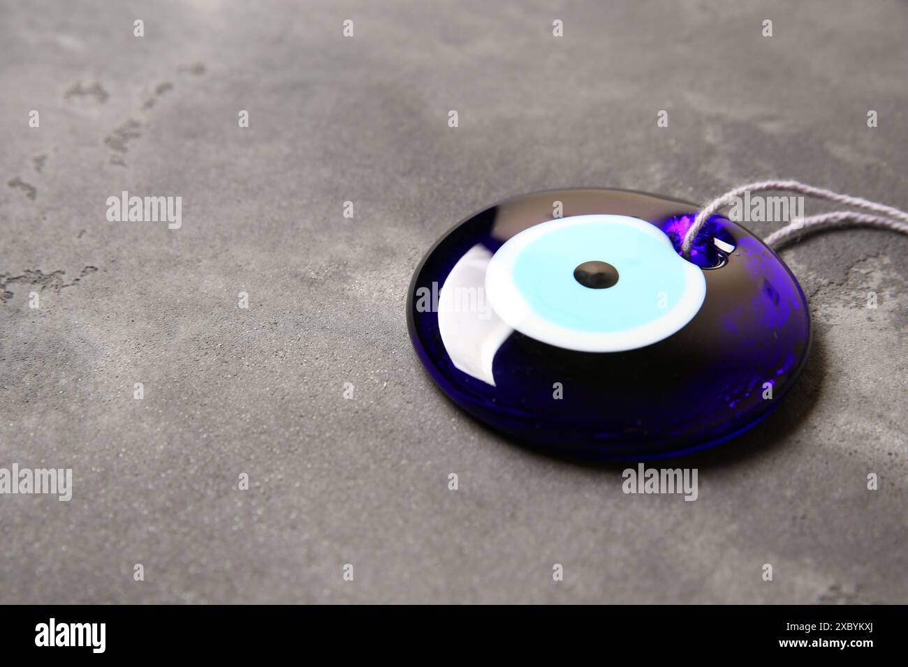 Traditional evil eye amulet on grey table, closeup. Space for text ...