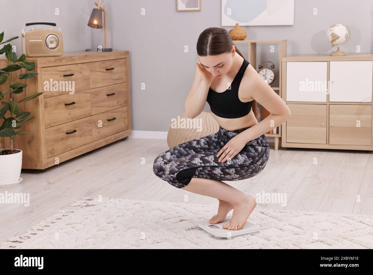 Woman measuring weight on floor scale at home Stock Photo - Alamy