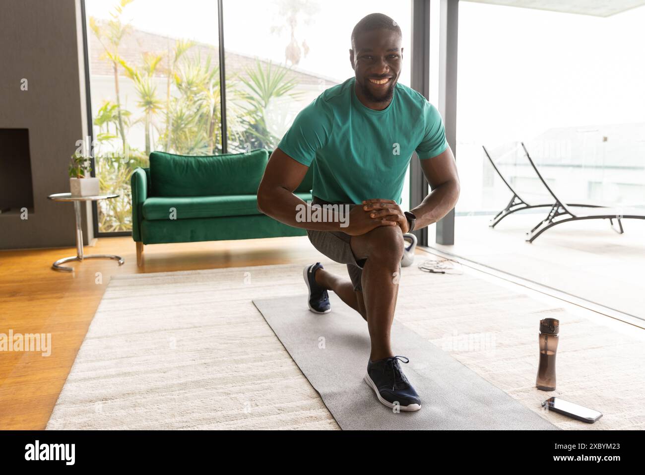 African American man working out stretching on yoga mat in modern ...