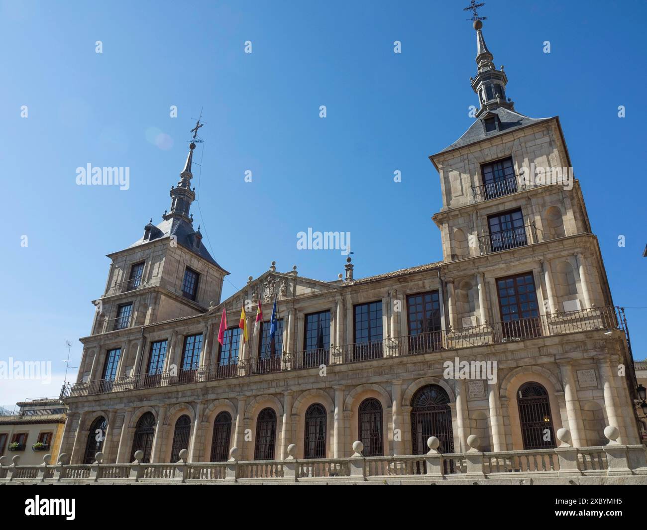 Large historic building with flags and two towers against a clear blue ...