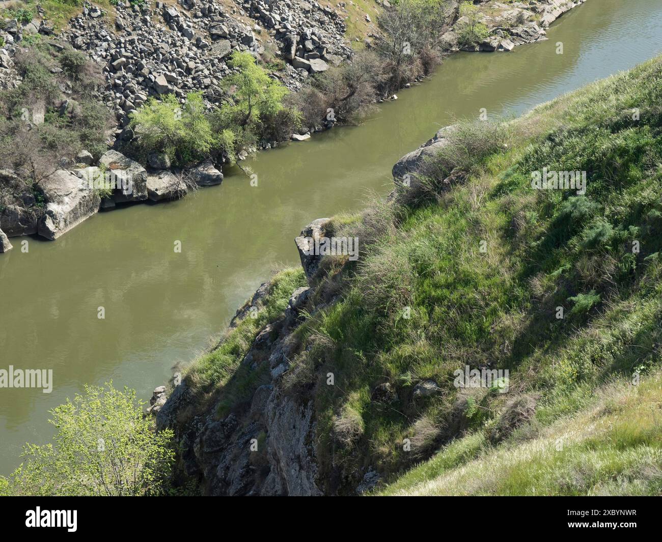 Natural riverbank with grass and rocks along a quiet river, Toledo ...