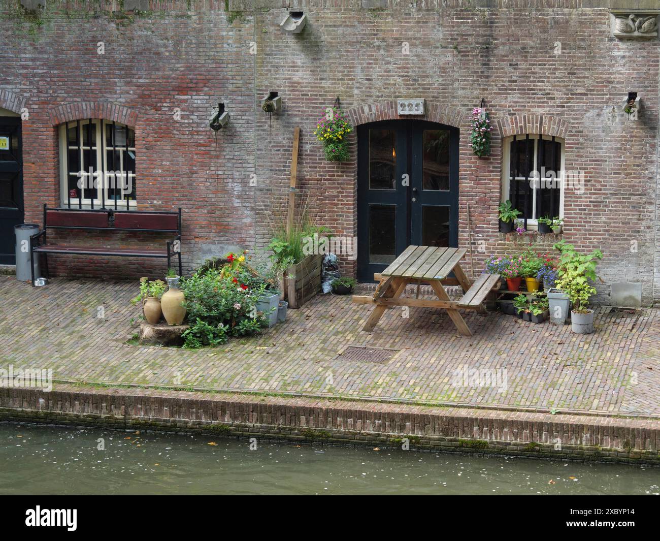 Rustic bank with picnic table, potted plants and brick wall along a ...