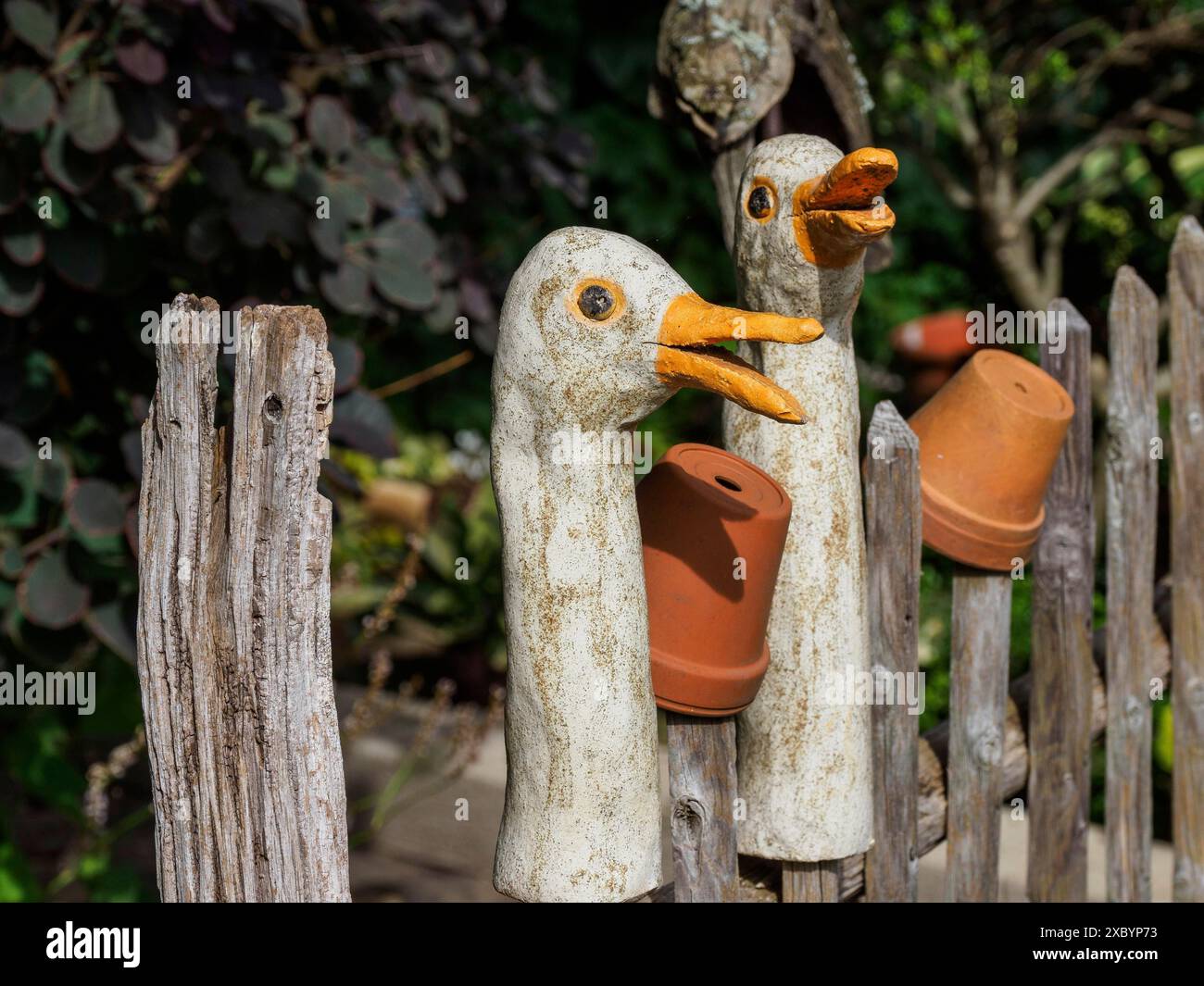 Wooden fence with decorative duck sculptures and clay pots that add a ...
