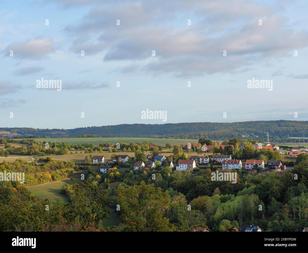 View of a village surrounded by lush nature and rolling hills under a ...