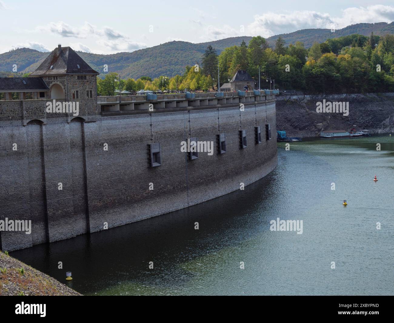 Massive dam impounding a river with neighbouring forest and hilly ...