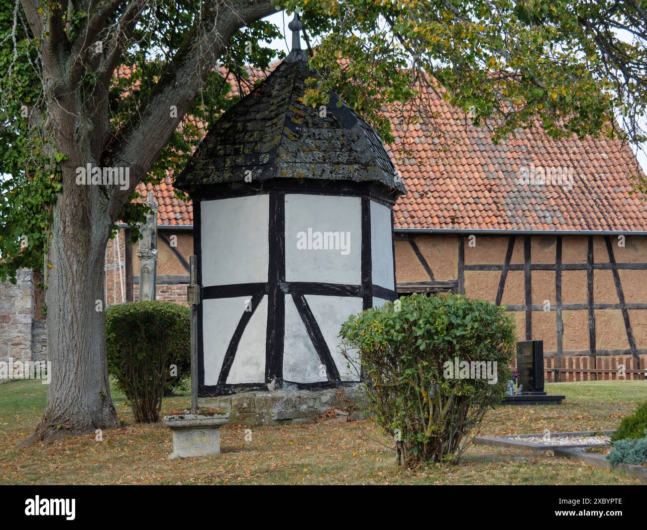 Small half-timbered house in a garden surrounded by trees in autumn ...