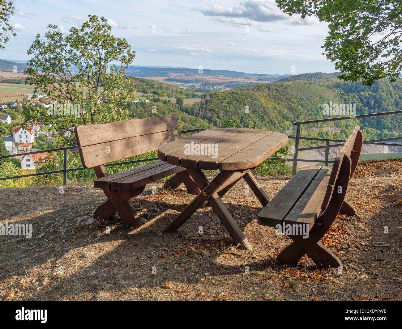 A wooden table with benches offers an idyllic view of the hilly ...
