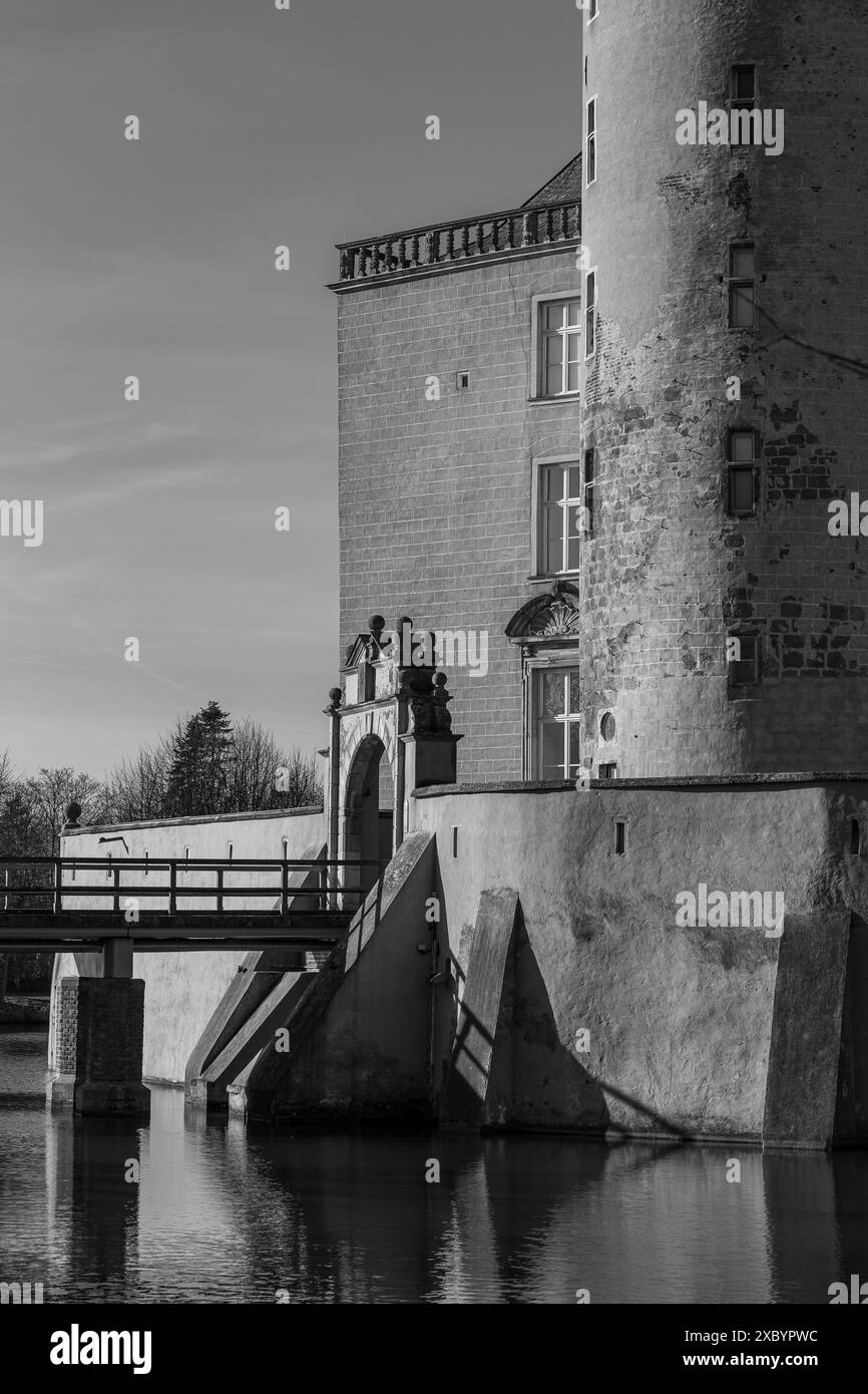A part of a historic castle with moat, bridge and a tower, shown in ...