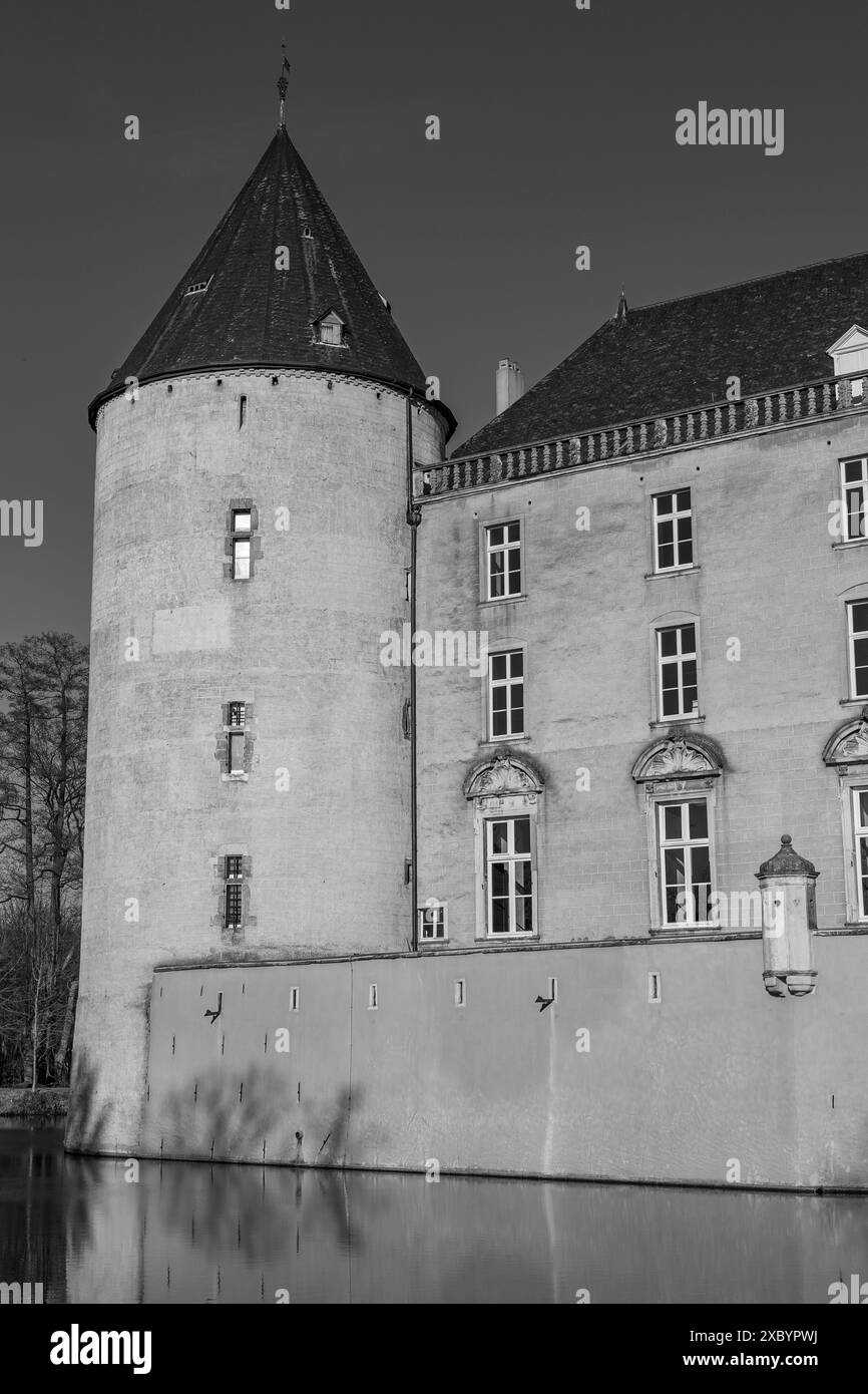 Part of a historic castle with a large round tower and moat, shown in ...