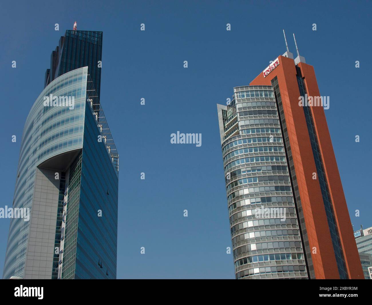 Two modern high-rise buildings with glass facades under a clear sky ...