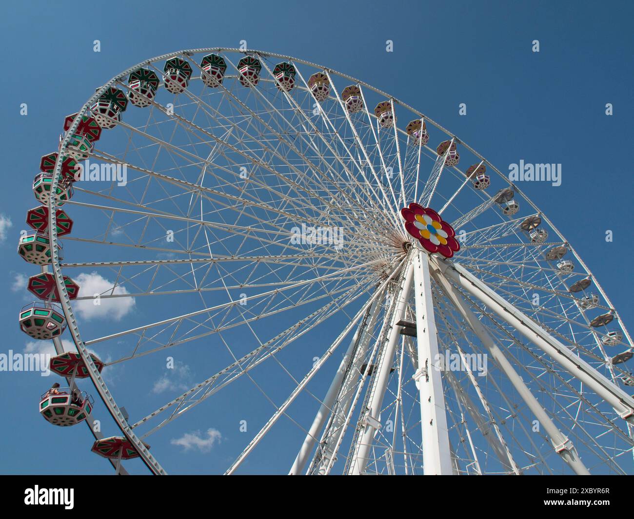 Large Ferris wheel with colourful cabins in front of a blue sky with ...