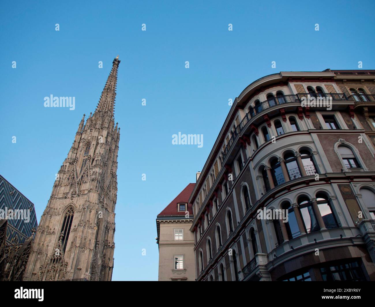 Spire of a historic church tower rises into the blue sky next to a ...