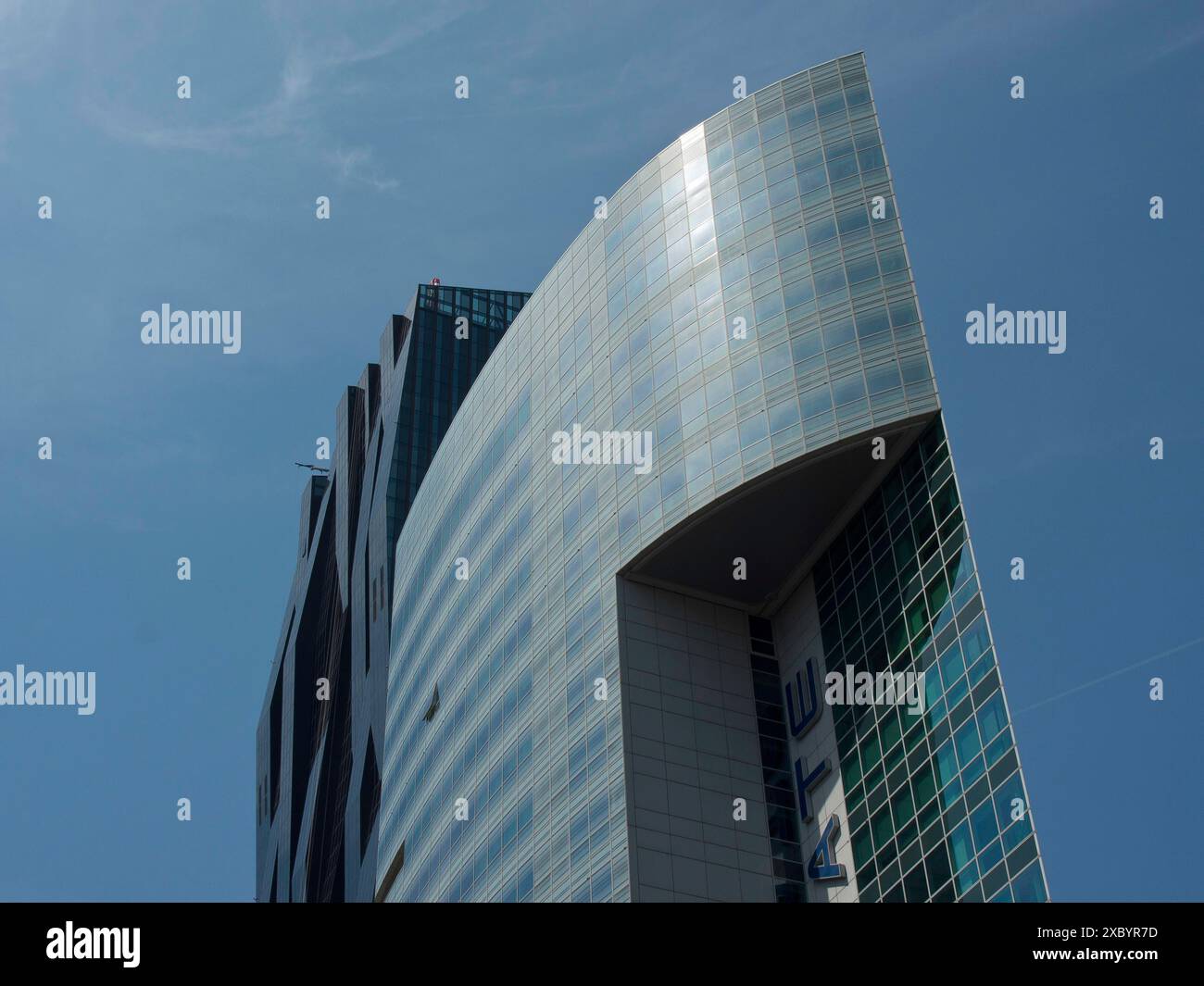 Facade of a modern, curved skyscraper with glass front against a blue ...