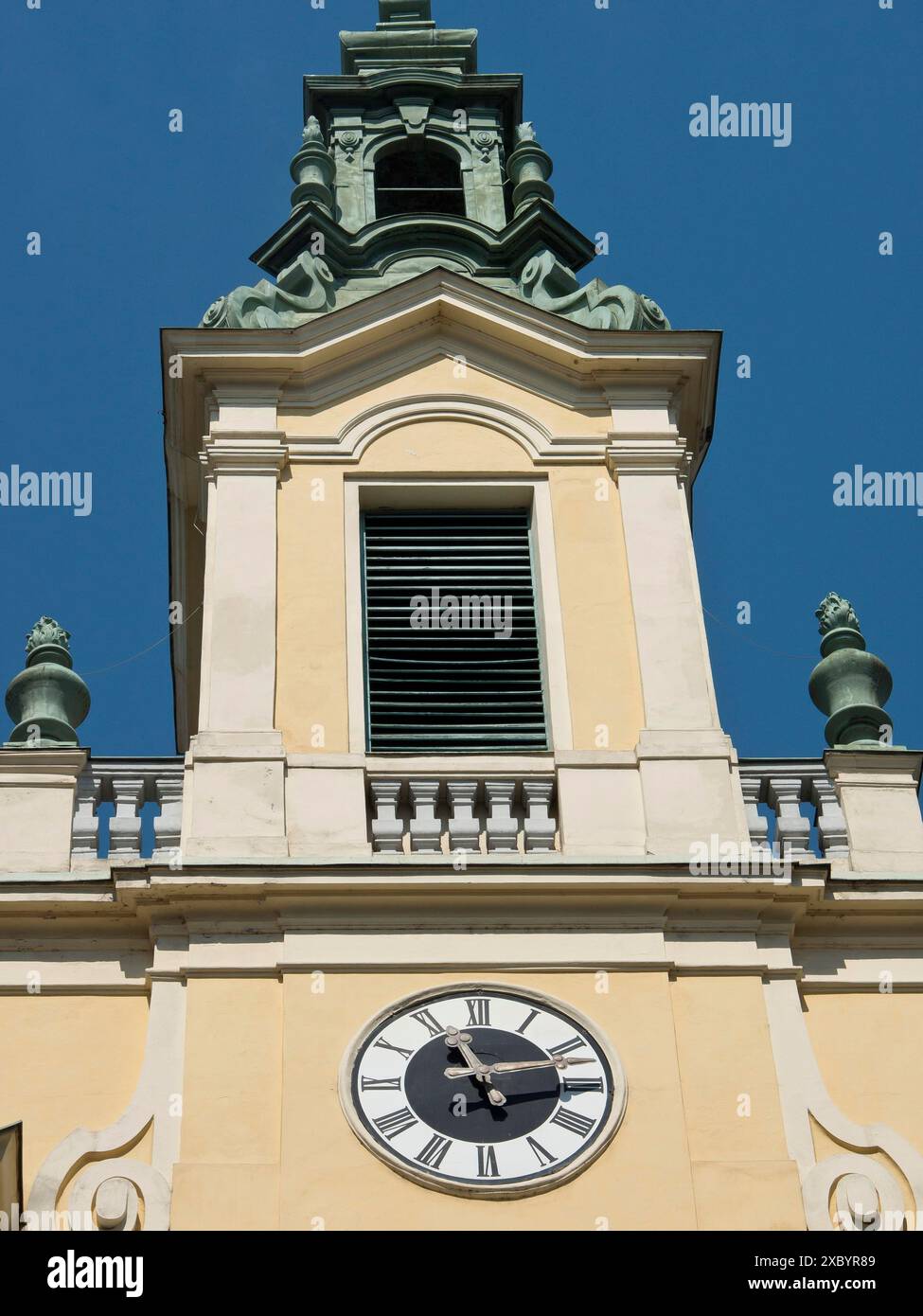 A baroque church tower with a clock and a yellow facade under a blue ...