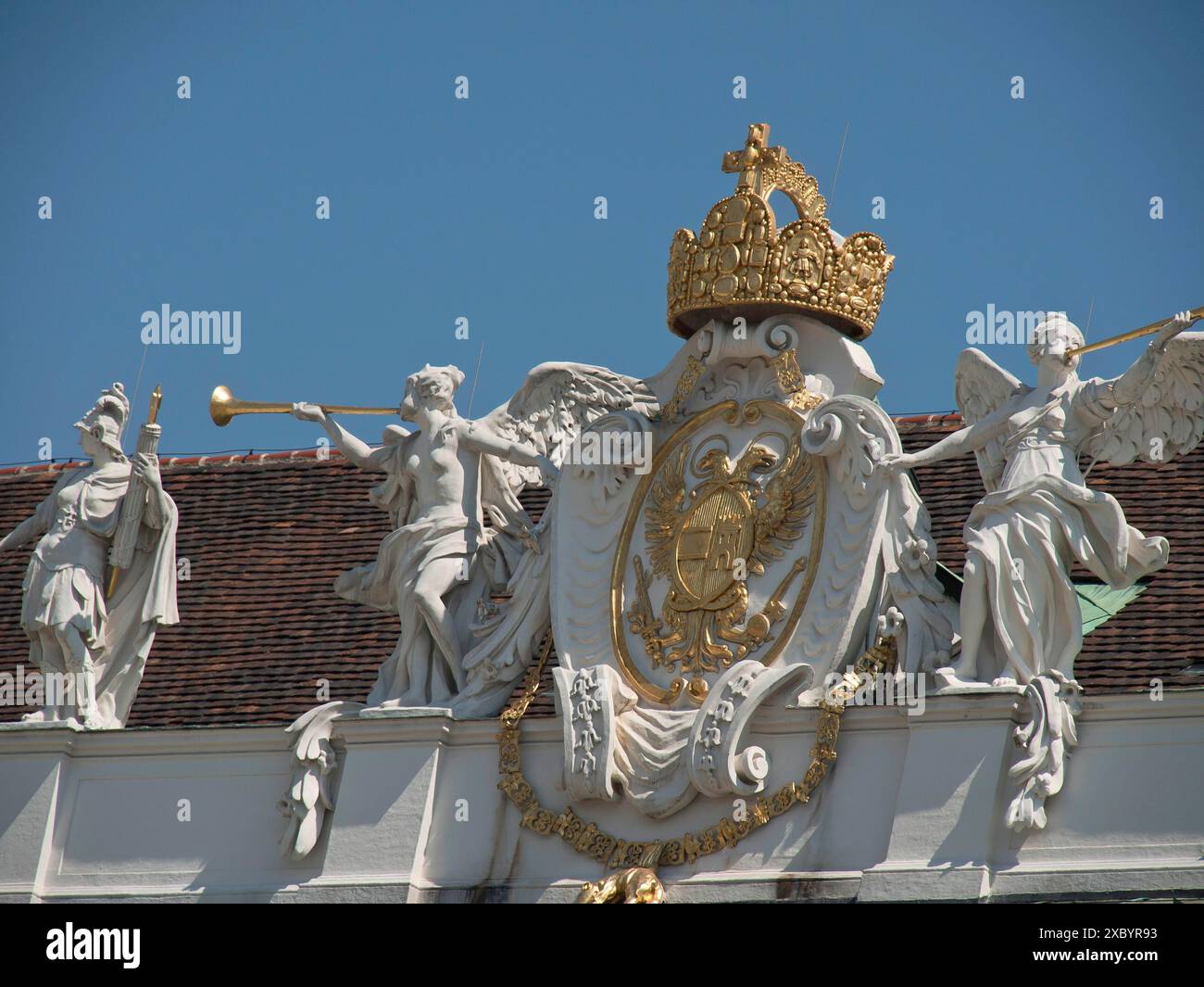 Baroque roof decoration with statues and a golden crown under a blue ...