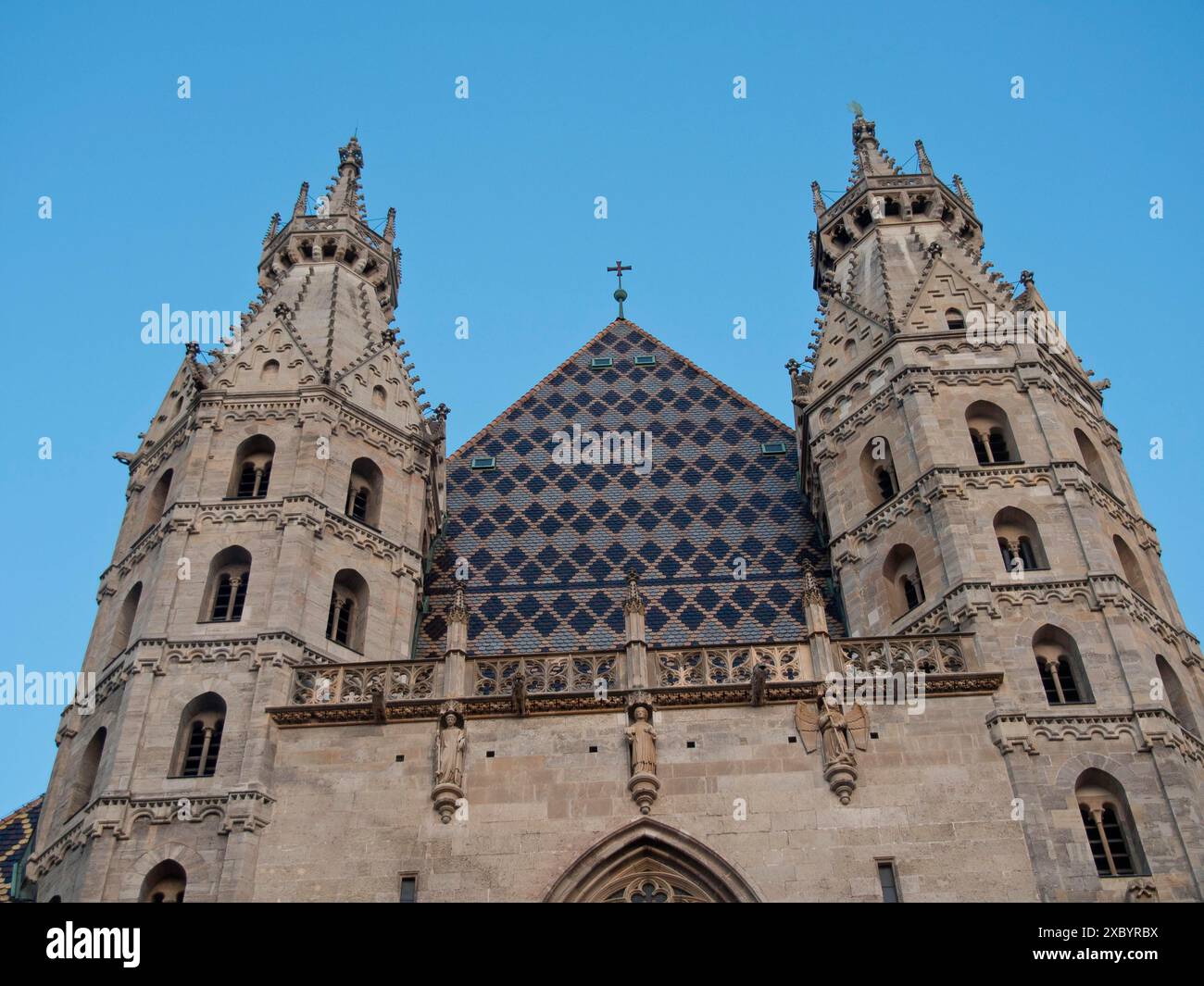 Front view of a Gothic cathedral with twin spires and a cross in the ...