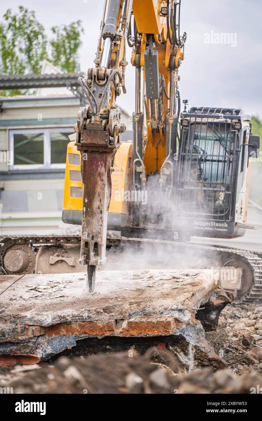 Excavator breaking concrete on a construction site, while a building ...