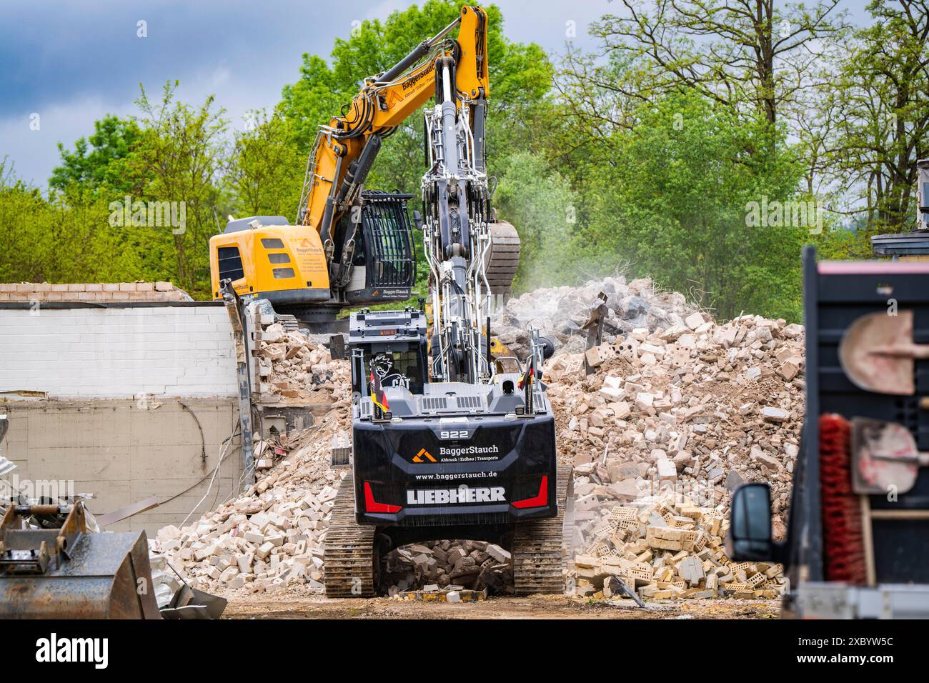 Two excavators on a construction site demolishing a building ...