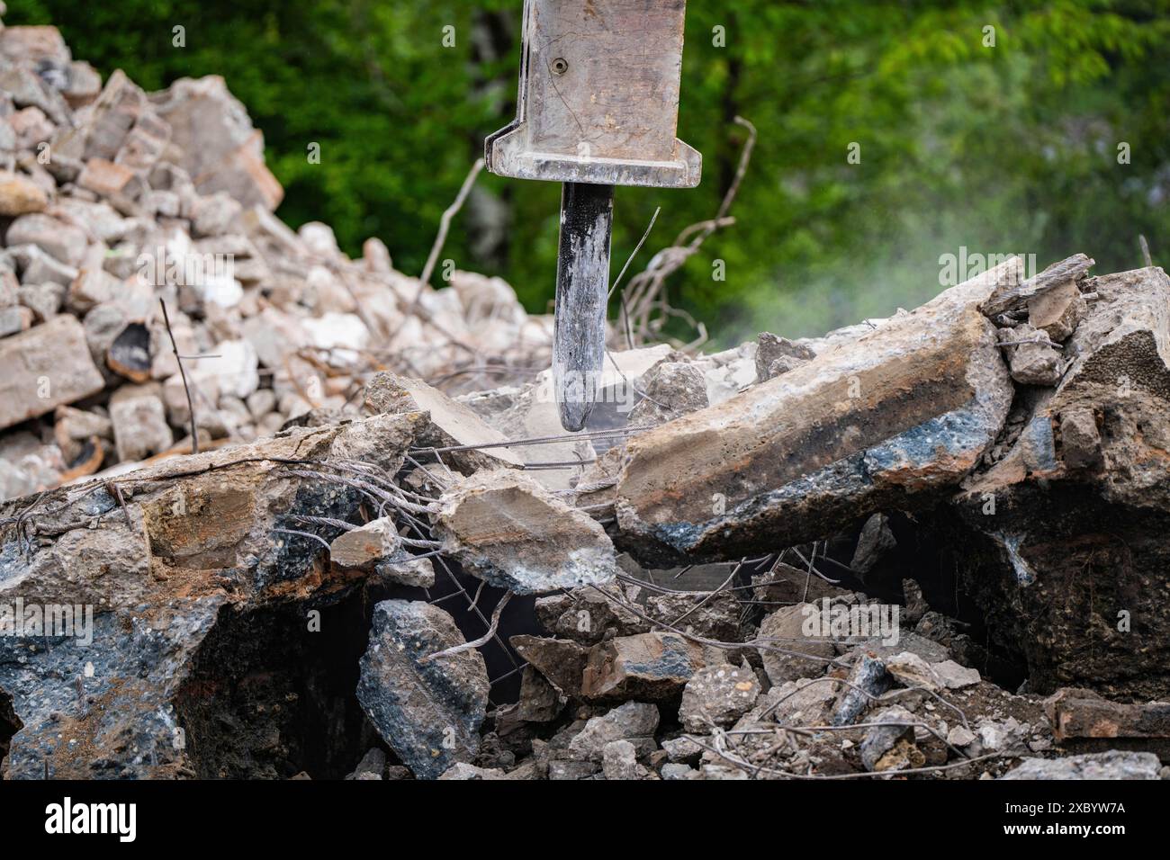 Excavator breaks up concrete and rubble and dust can be seen on a ...