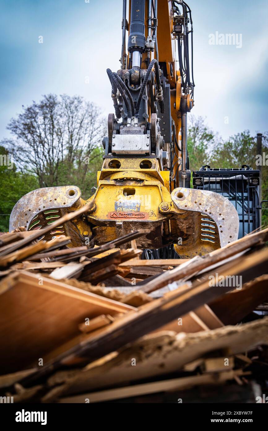 Large demolition machine crushing wood debris in front of a wooded ...