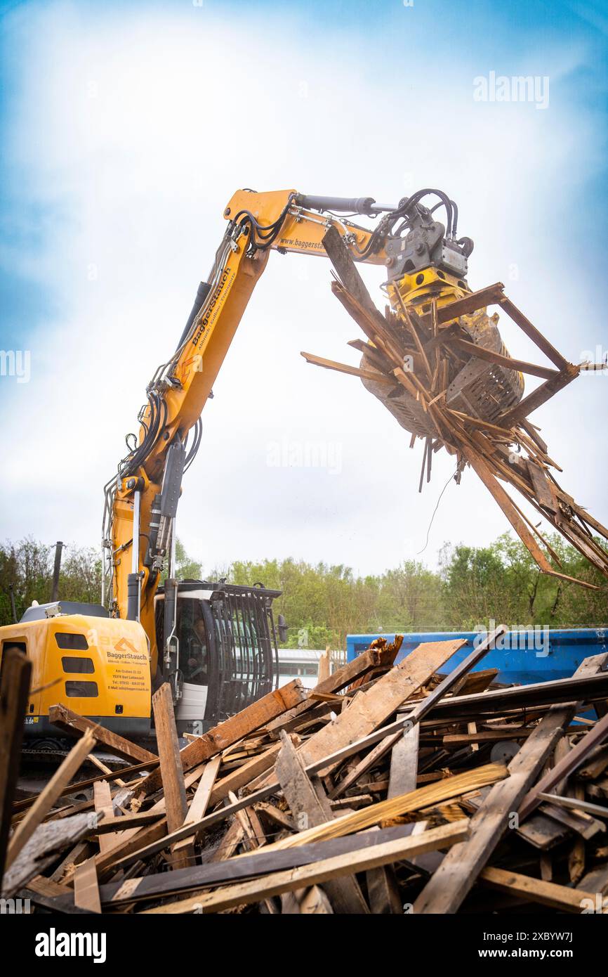 An excavator during demolition work, moving wood and metal under a ...