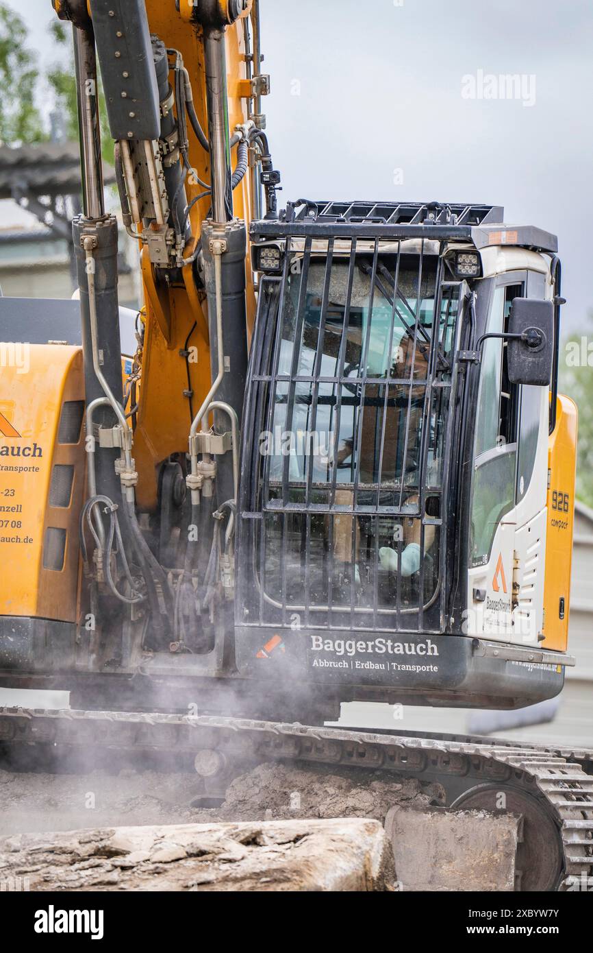 Excavator during demolition, breaking up concrete. The driver is ...