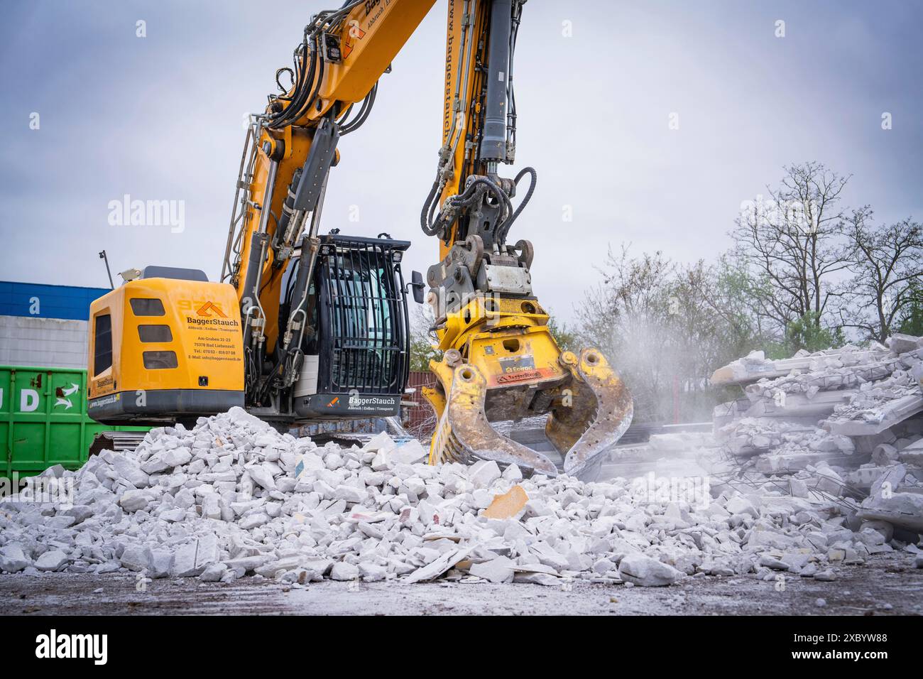 Large yellow excavator with metal grab shredding rubble on a ...