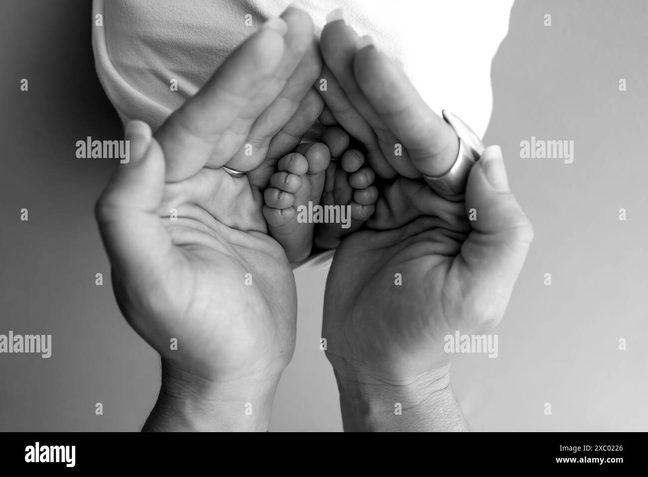 The palms of the father and mother are holding the foot of newborn baby ...