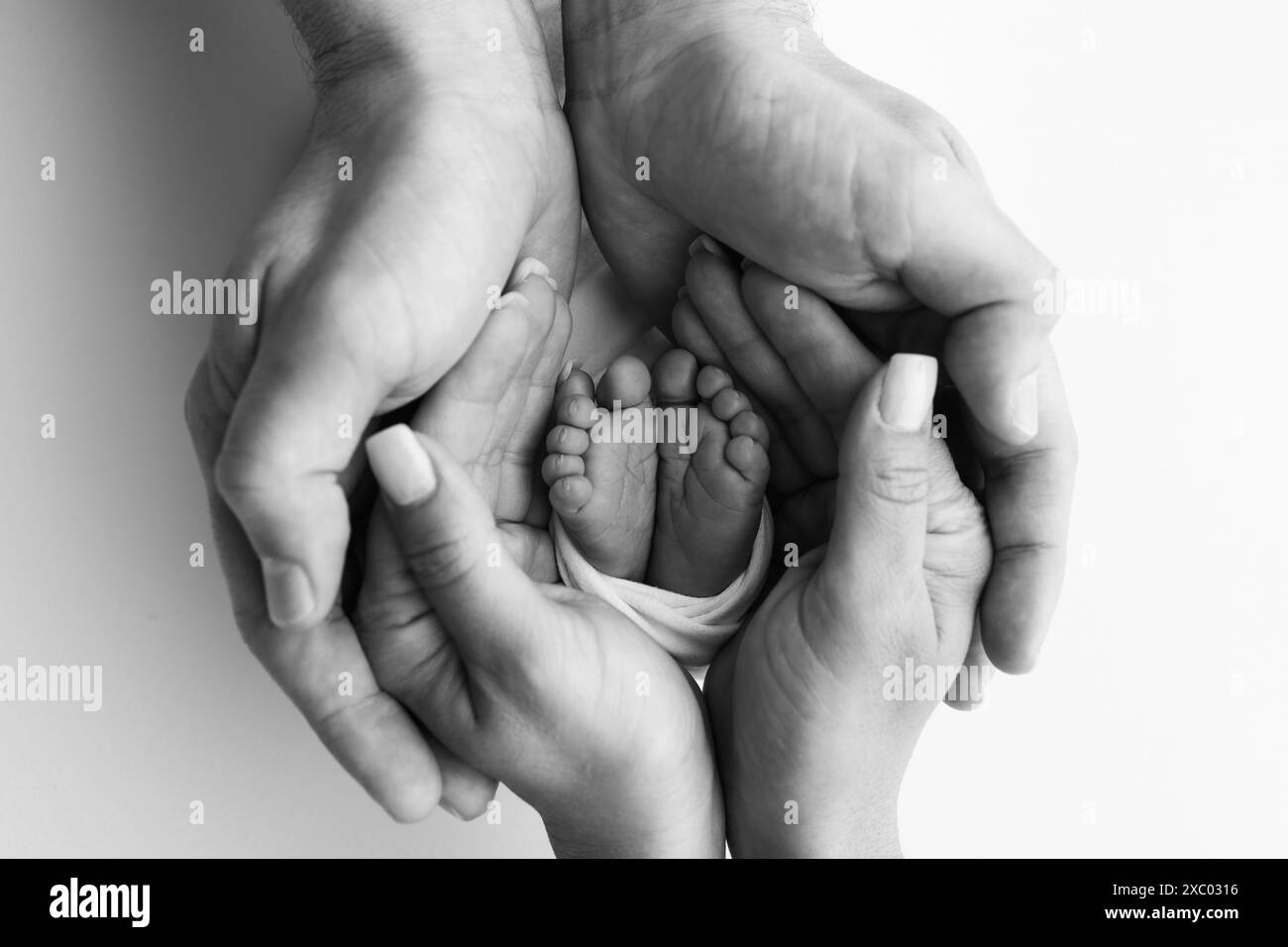The palms of the father, the mother are holding the foot of the newborn ...