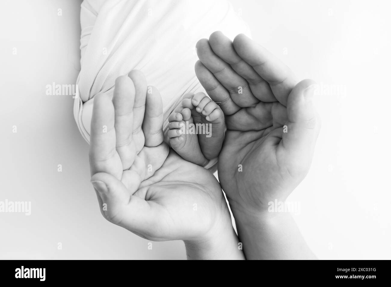 The palms of the father, the mother are holding the foot of the newborn ...