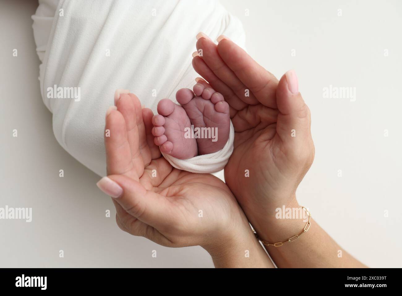 The palms of the father, the mother are holding the foot of the newborn ...