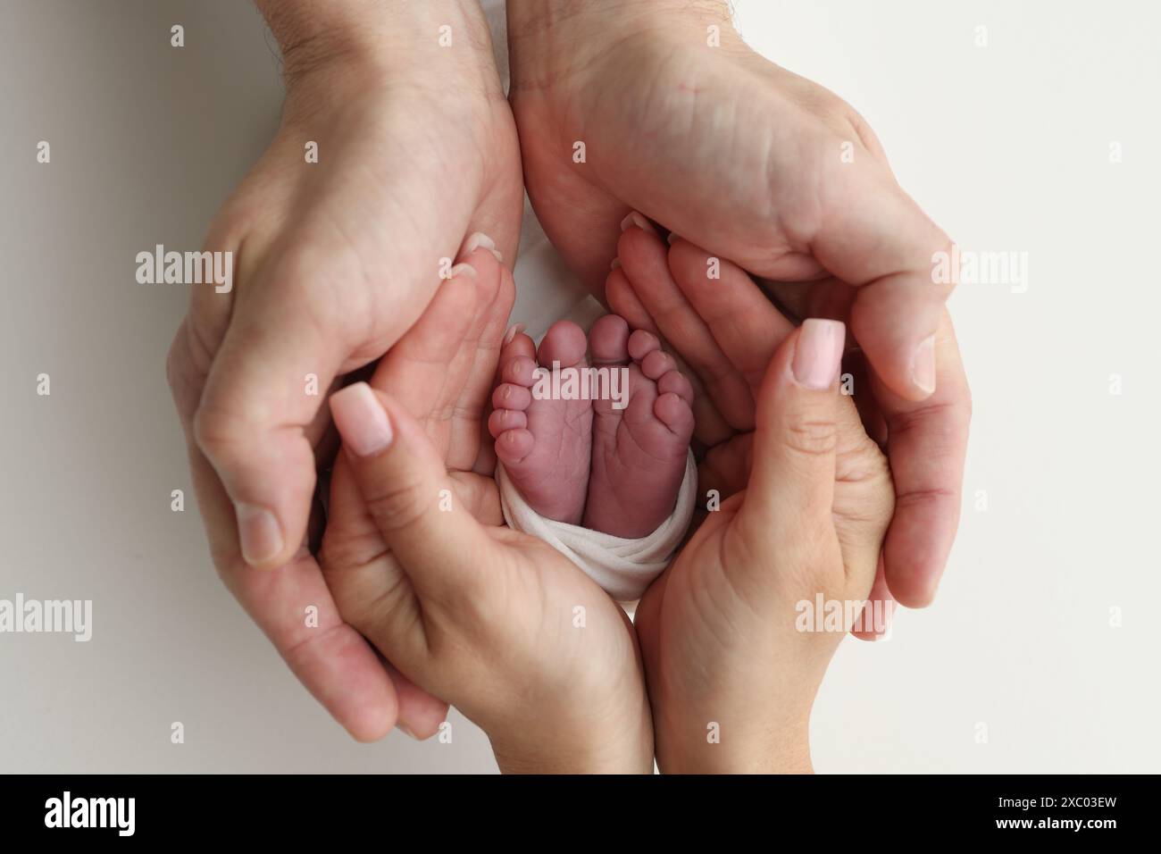 The palms of the father, the mother are holding the foot of the newborn ...