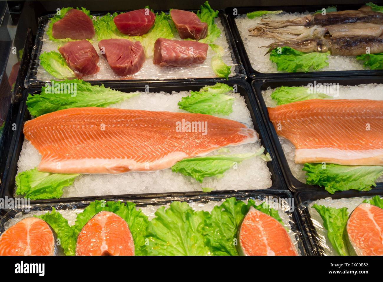 Fresh fish fillets and steaks on display at a seafood market counter ...