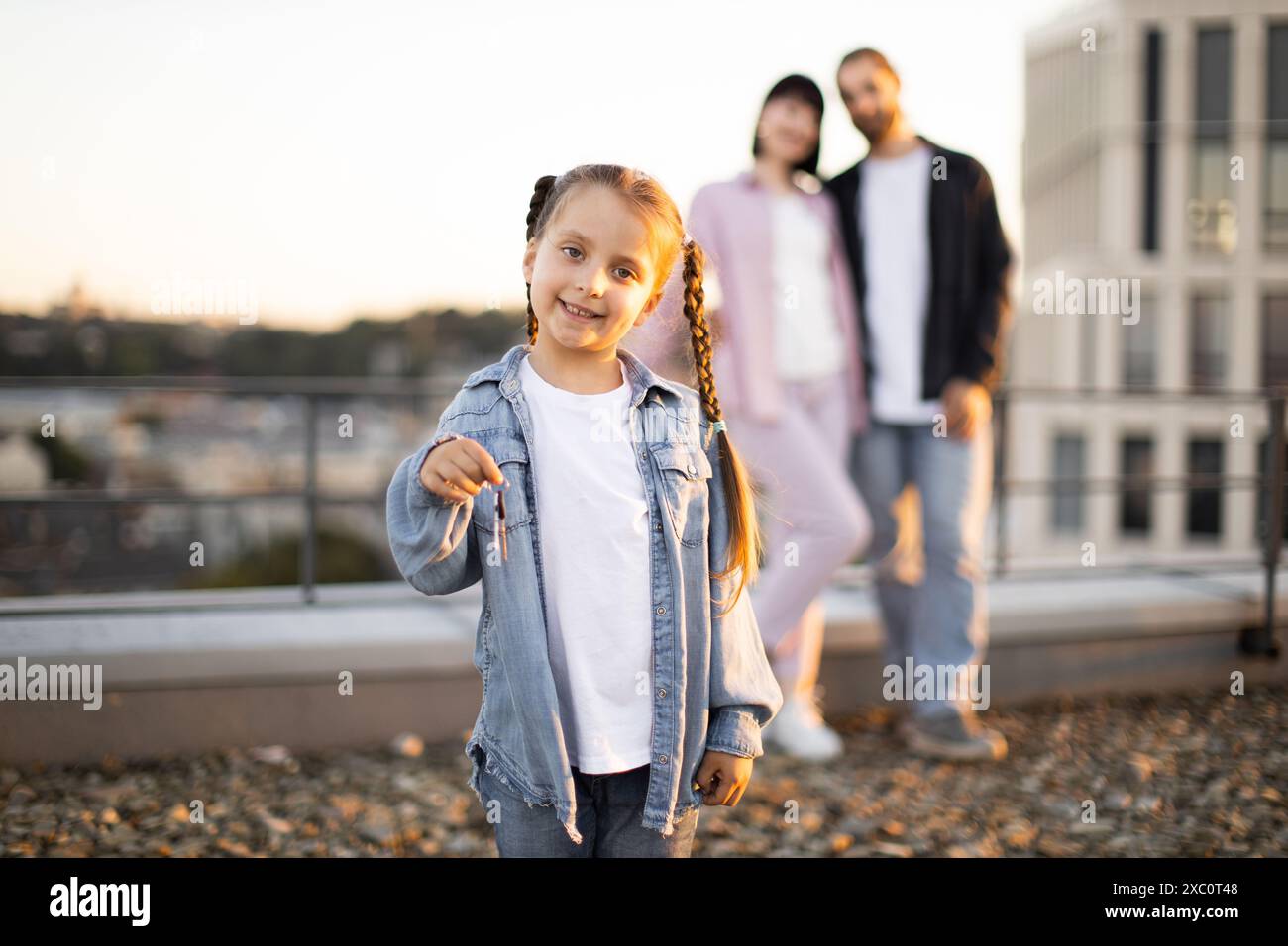 Little girl holding key with family in background on rooftop Stock ...