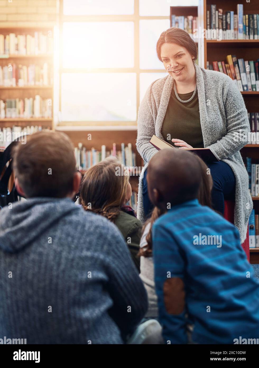 Library, children and teacher reading book, education and learning with ...