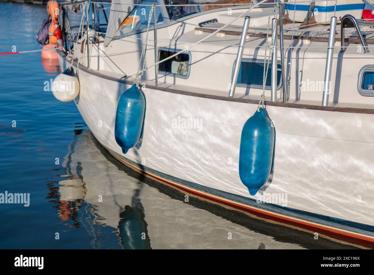 Docked boat with blue fenders hanging alongside vessel, sunny summer ...