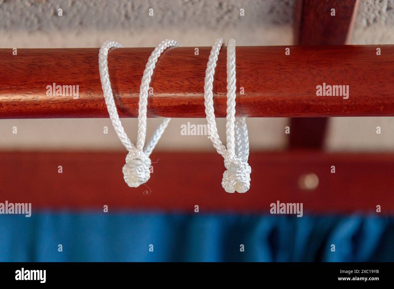 Soft shackles from white dyneema rope on a wooden grabrail on a ...