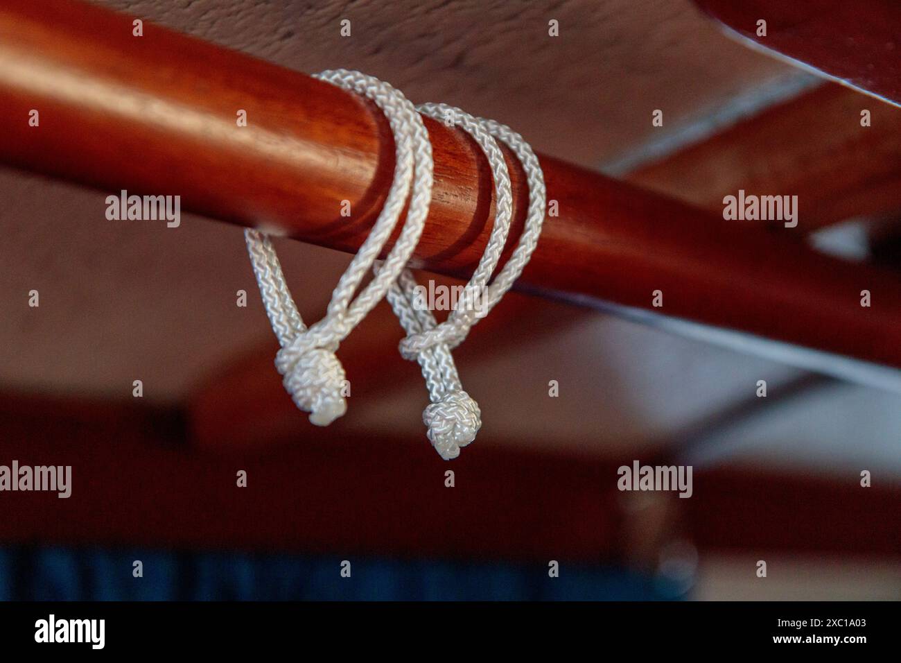 Soft shackles from white dyneema rope on a wooden grabrail on a ...