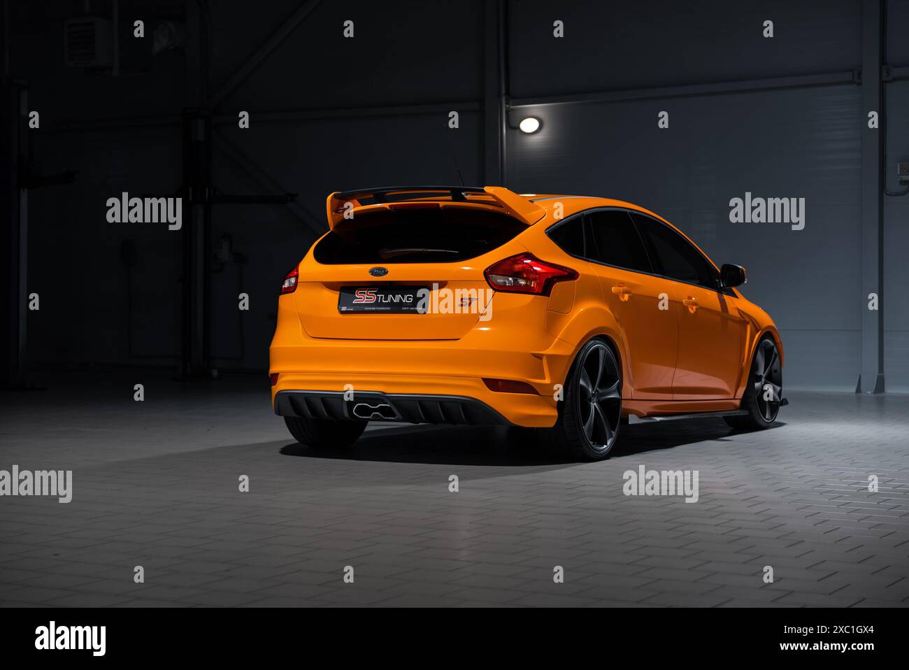 orange Ford Focus ST in front of grey wall. Three quarter rear view of ...