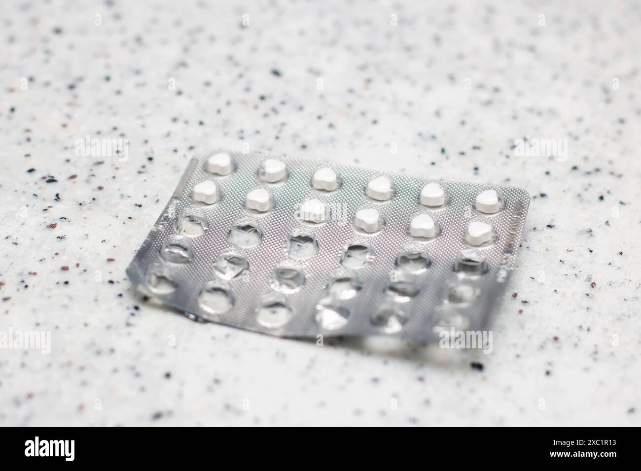 A blister pack of pills is placed on a silver counter top, creating a ...