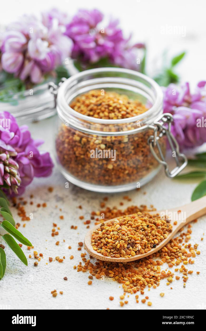 Healthy bee pollen grains. Bee pollen on a glass jar and acacia flowers ...