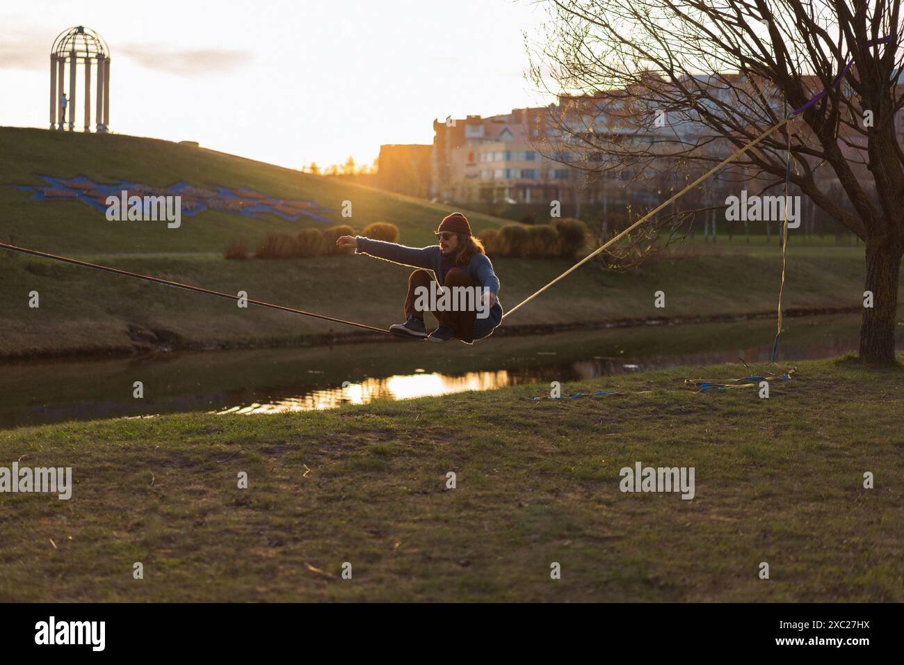 Young man sitting on a slackline Stock Photo - Alamy