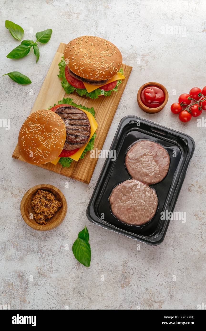 a ready-made burger and fresh raw burger patties next to it Stock Photo ...