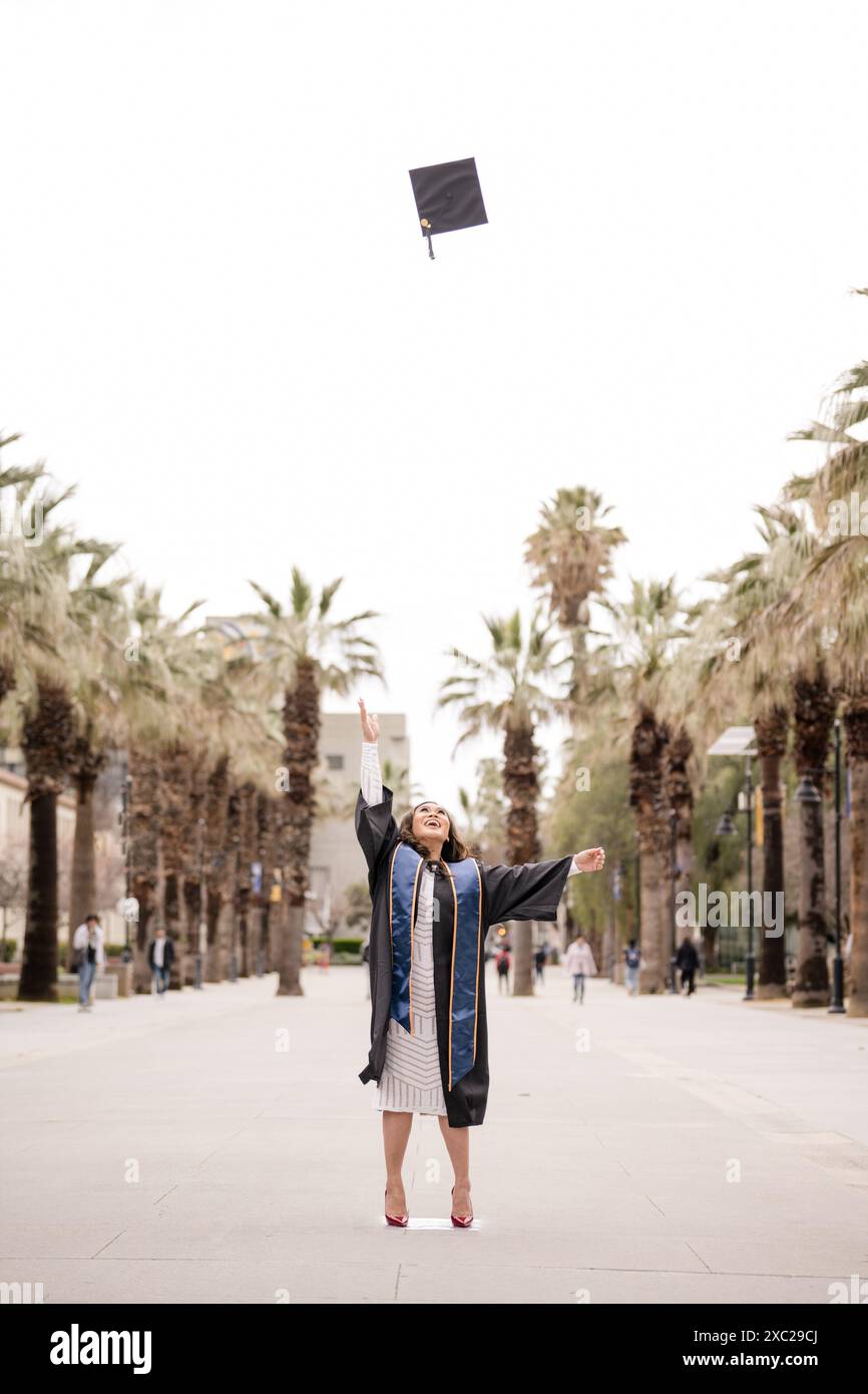 Excited Asian women in graduation gown throwing cap in the air Stock ...