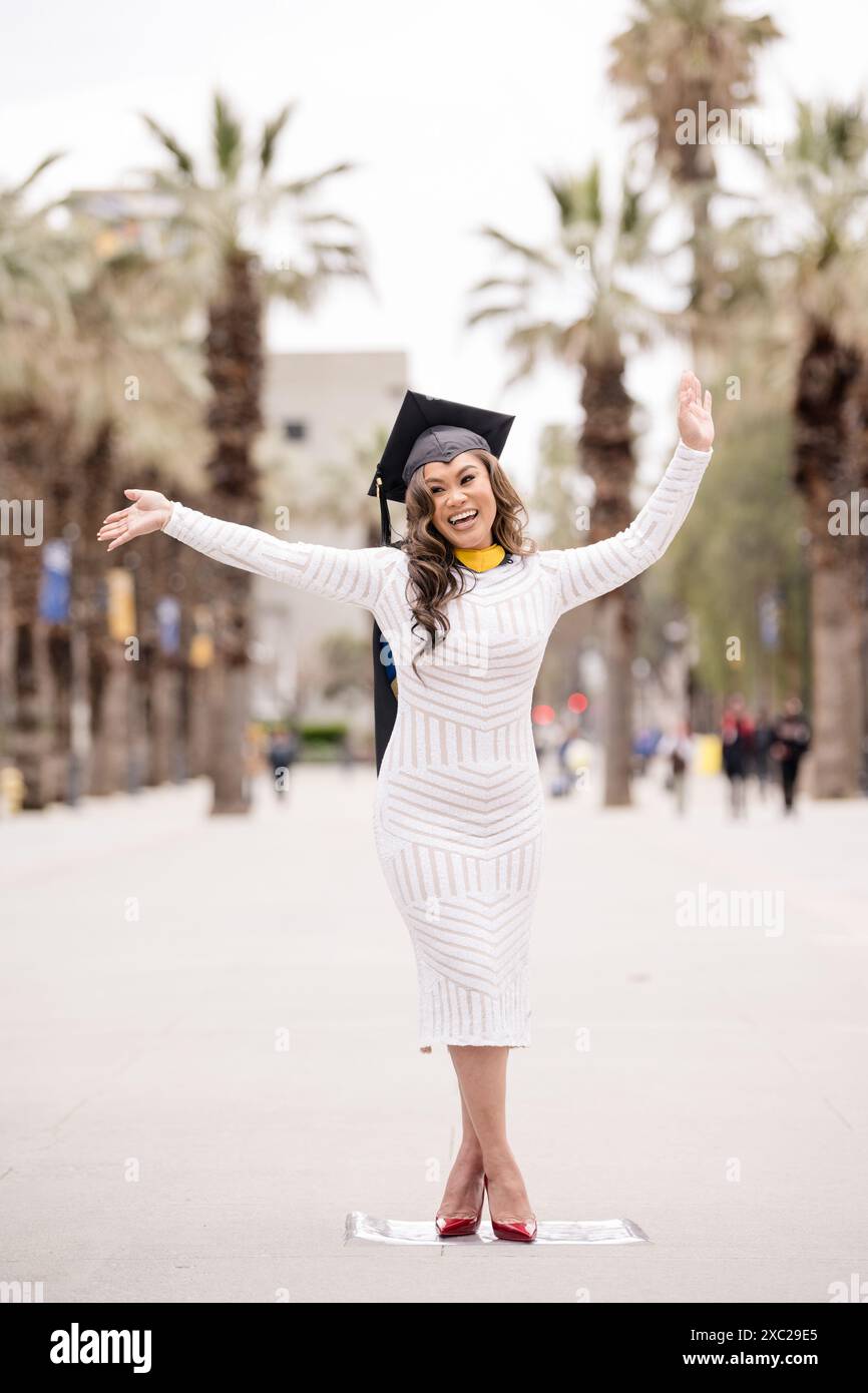 Women in white dress and graduation cap, throwing hands up in ex Stock ...