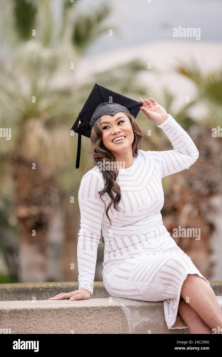 Smiling Asian women holding her graduation cap and wearing white Stock ...