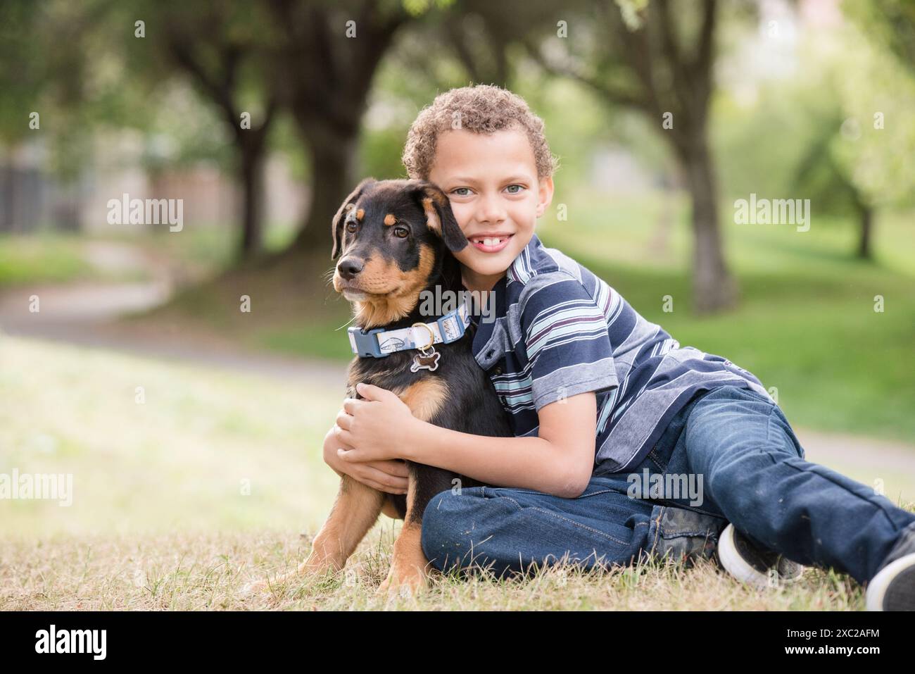 Boy hugging puppy and smiling at camera Stock Photo - Alamy