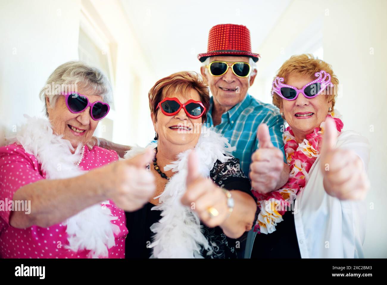 Thumbs up, smile and sunglasses with senior friends in hallway of ...